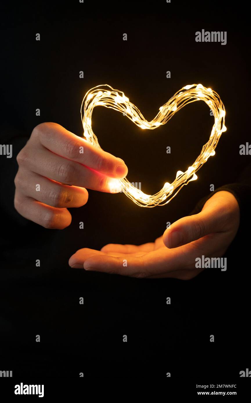 Hand holding heart made from lights on black background Stock Photo - Alamy