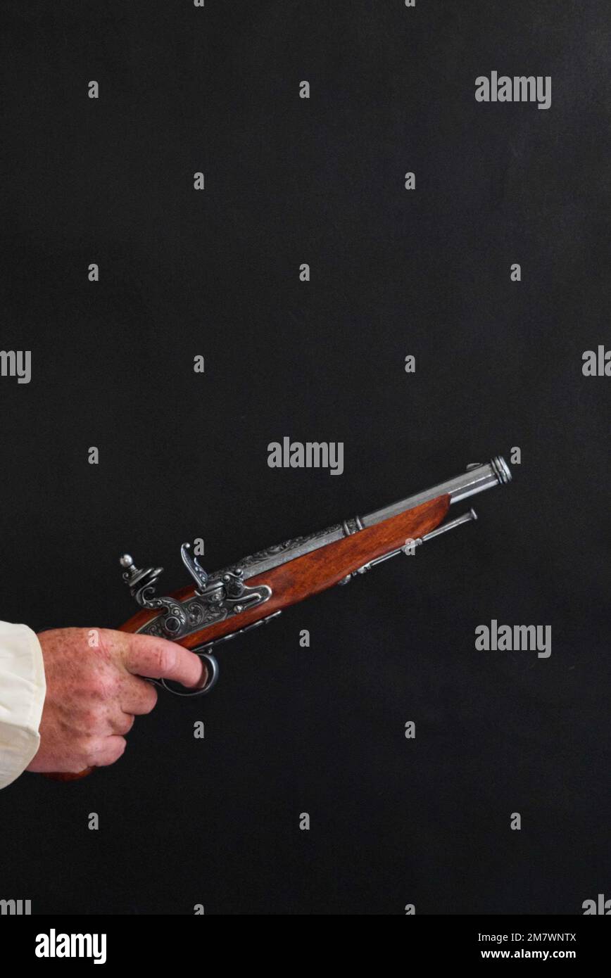 hand holding flintlock pistol against black background Stock Photo - Alamy