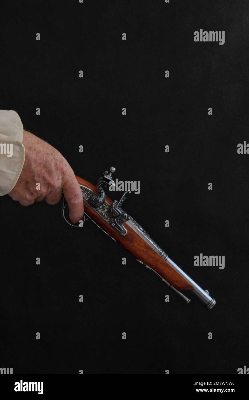 hand holding flintlock pistol against black background Stock Photo - Alamy