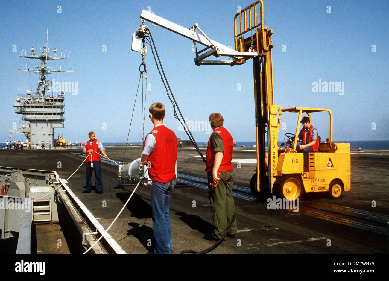 Ordnancemen lower a Sea Sparrow (RIM-7) missile container from the ...