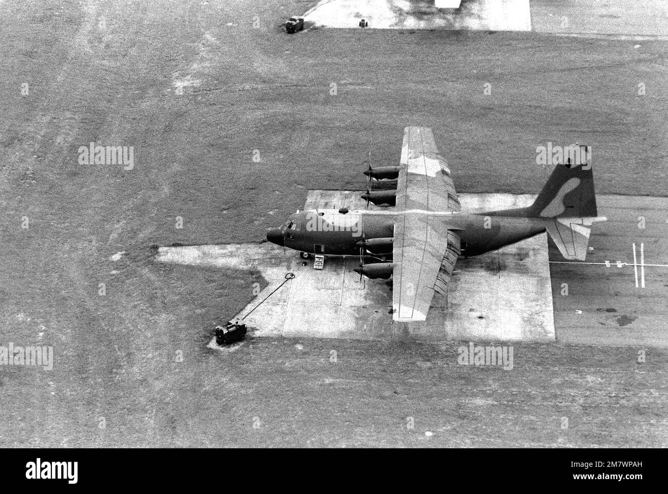 An aerial view of a C-130 Hercules aircraft parked on the flight line. Base: Naval Air Station ...