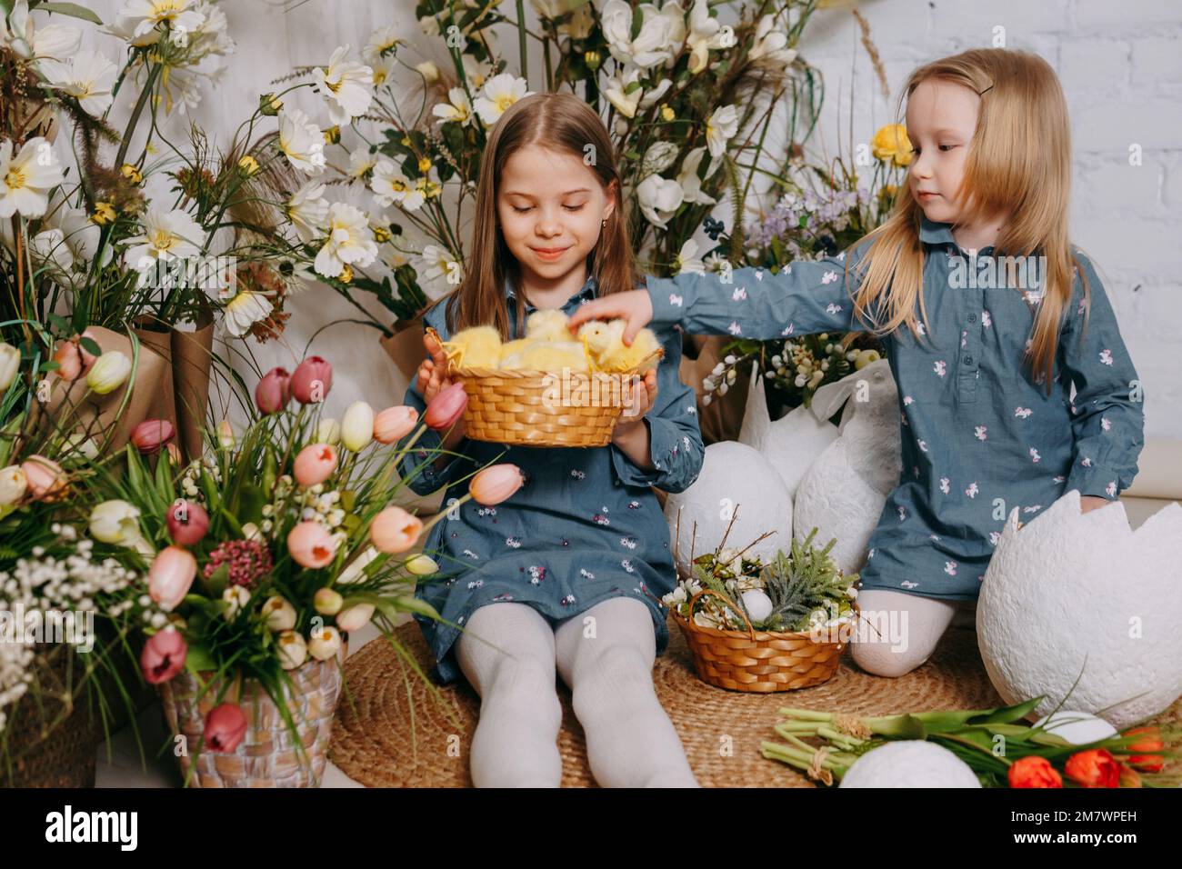 Two girls in a beautiful Easter photo zone with flowers, eggs, chickens ...