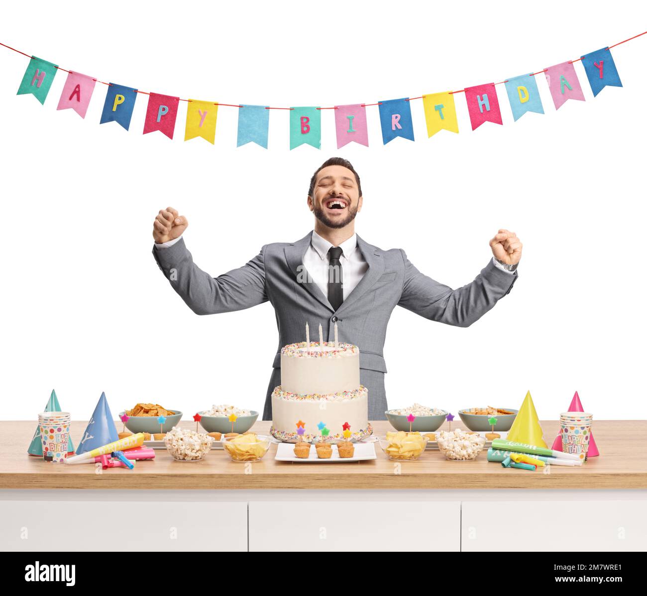 Young man in a suit celebrating birthday behind a counter with a cake ...