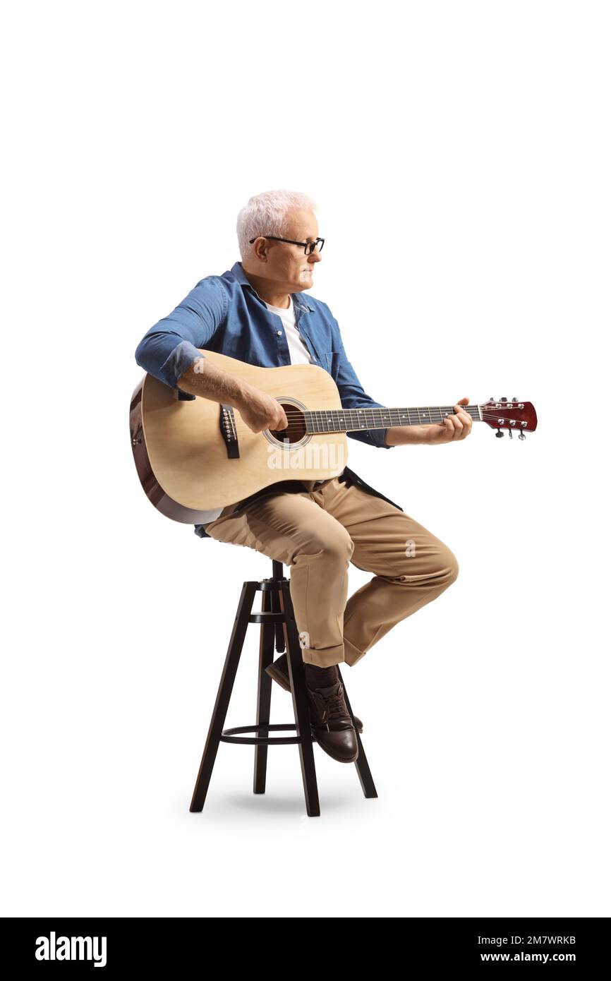 Man sitting on a chair and playing an acoustic guitar isolated on white ...