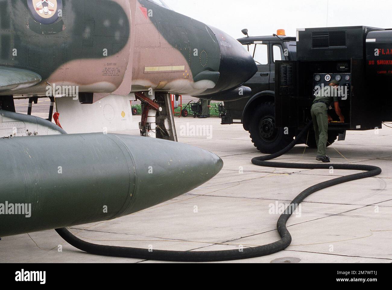 An airman prepares to set a fuel truck's panel to refuel an F-4C ...