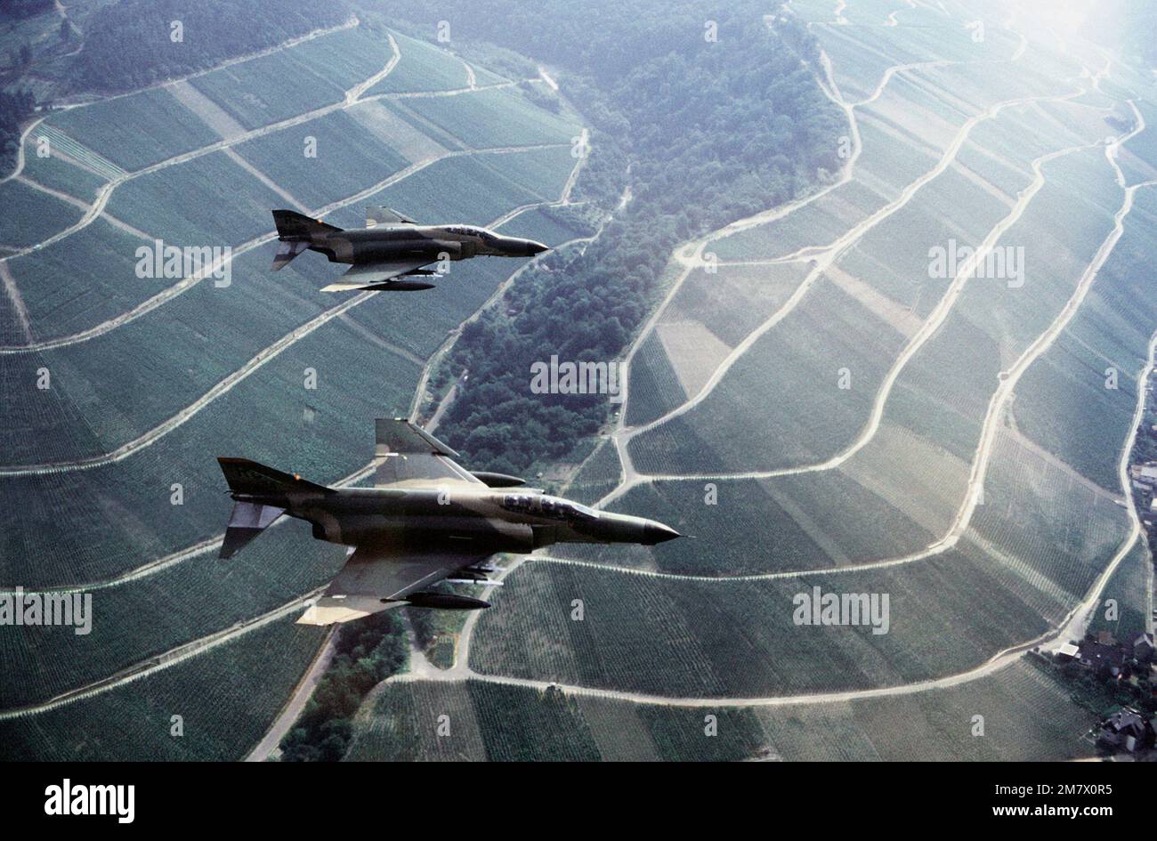 An air-to-air right side view of two F-4E Phantom II aircraft. The ...