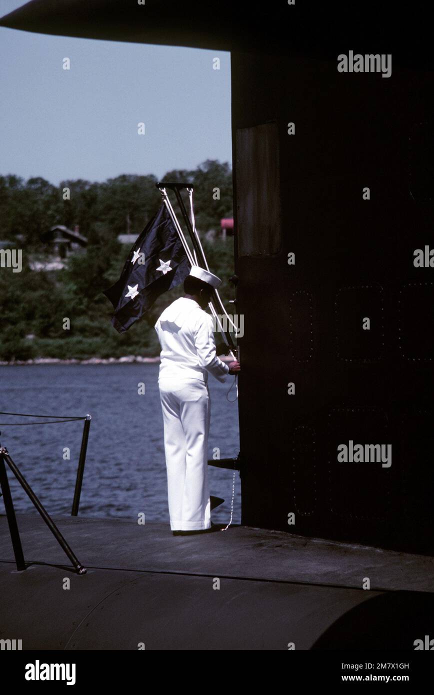 A crewman raises the admiral's flag aboard the nuclear-powered attack ...