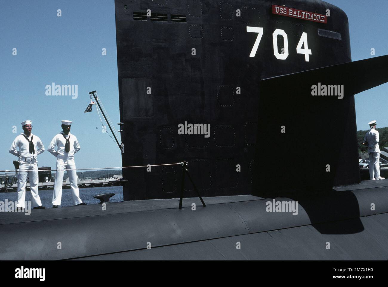 Two crewmen stand at parade rest on the deck of the nuclear-powered attack submarine USS ...