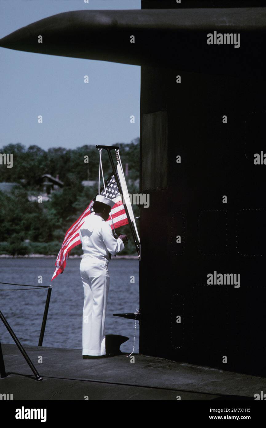 A crewman raises the United States flag aboard the nuclear-powered ...