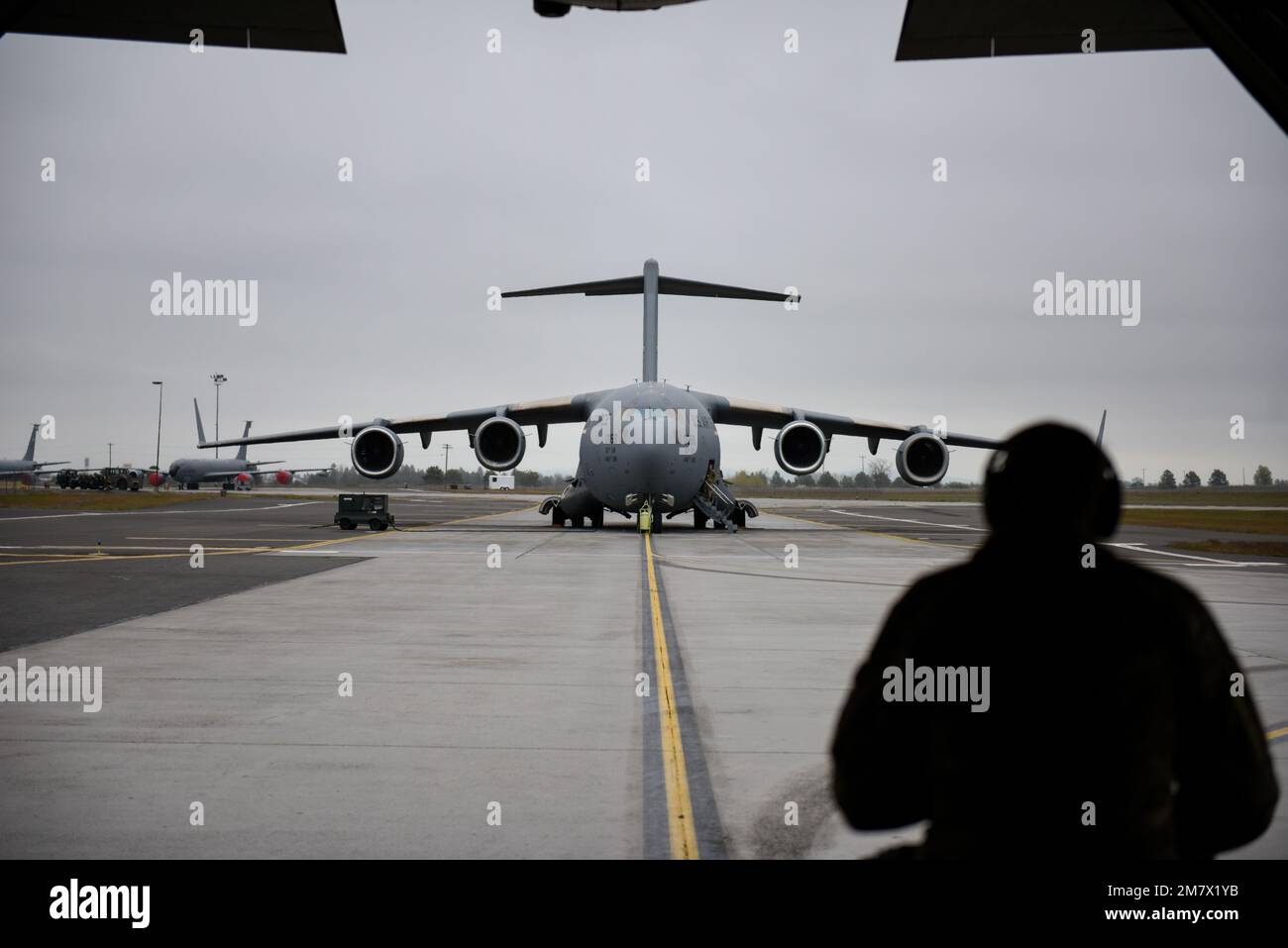 A Lockheed C-130 Hercules taxis on the runway with a Boeing C-17 ...