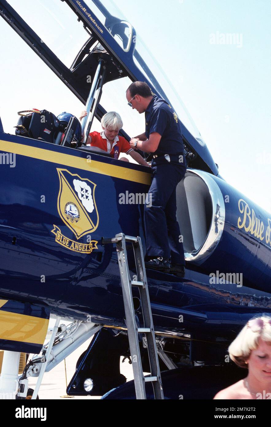 A member of the Blue Angels Flight Demonstration Team helps a child ...