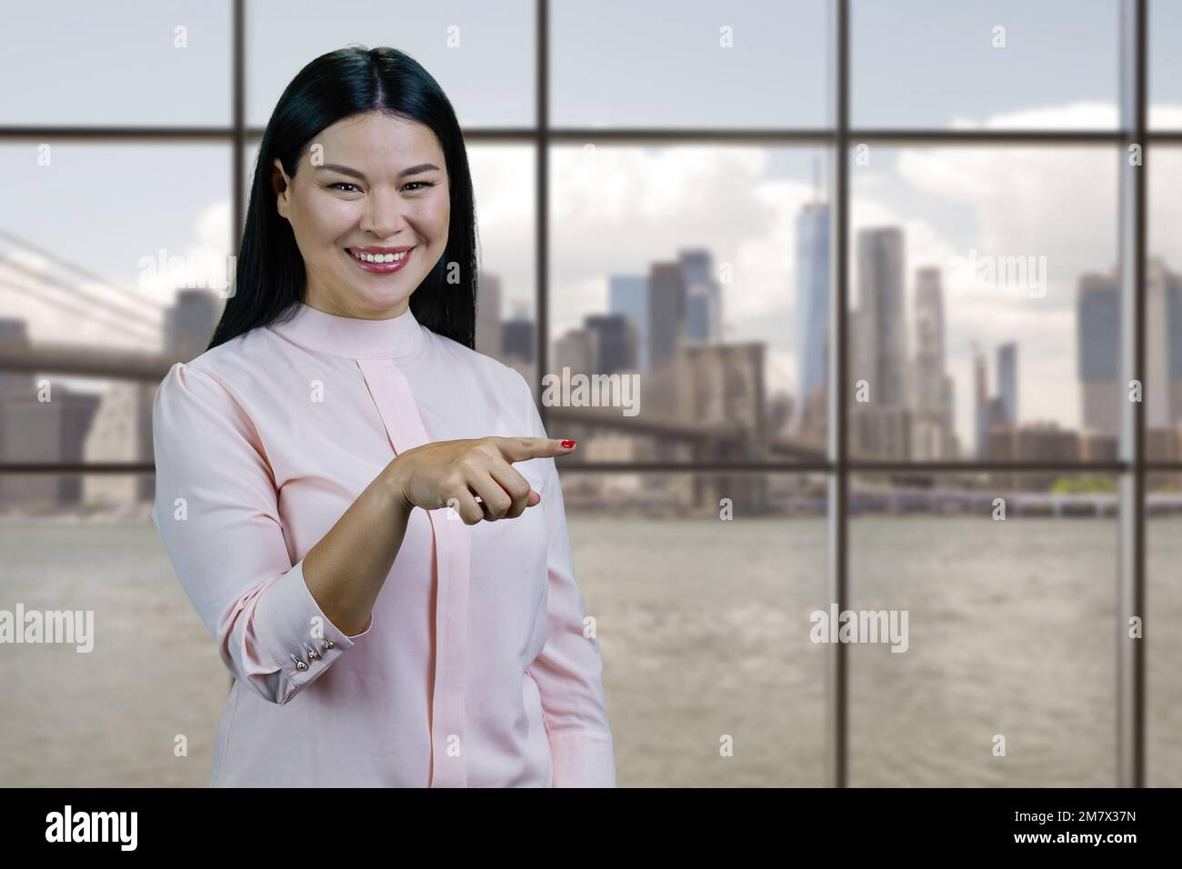 Portrait of young asian woman pointing at something. Checkered windows ...