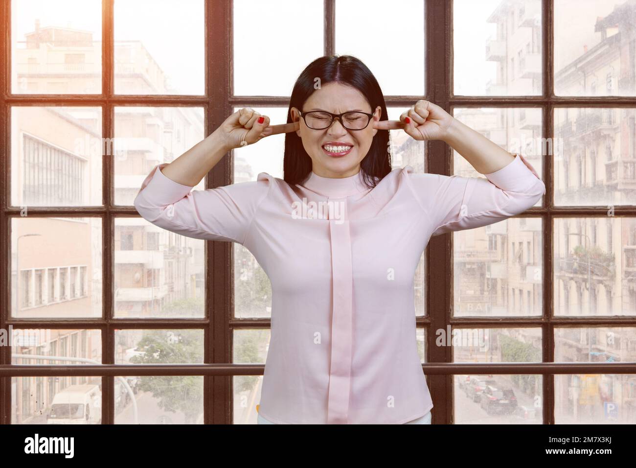 Stressed young businesswoman covering ears with fingers trying not to ...