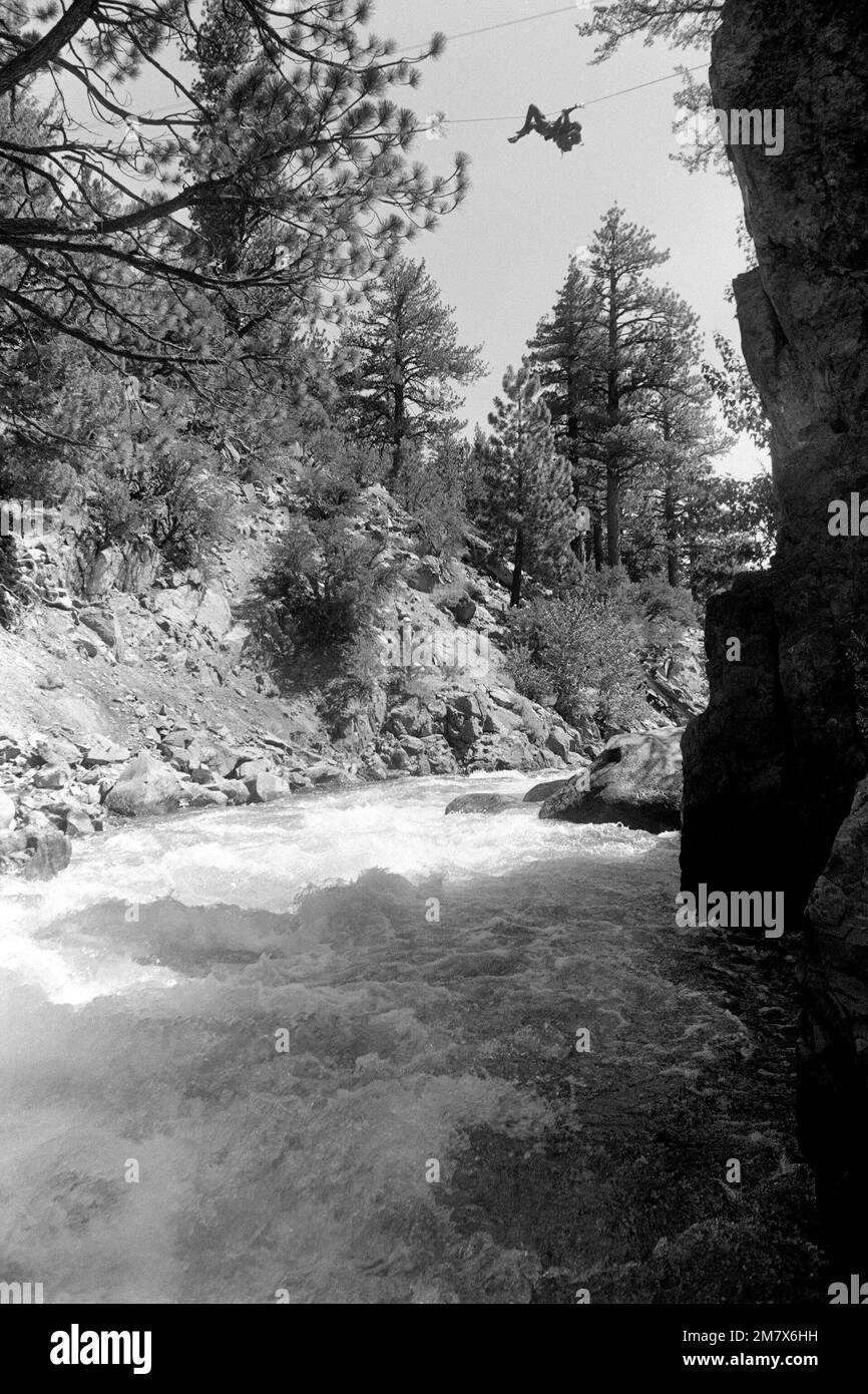 A low angle view of a Marine using a one-rope bridge to cross a deep ...