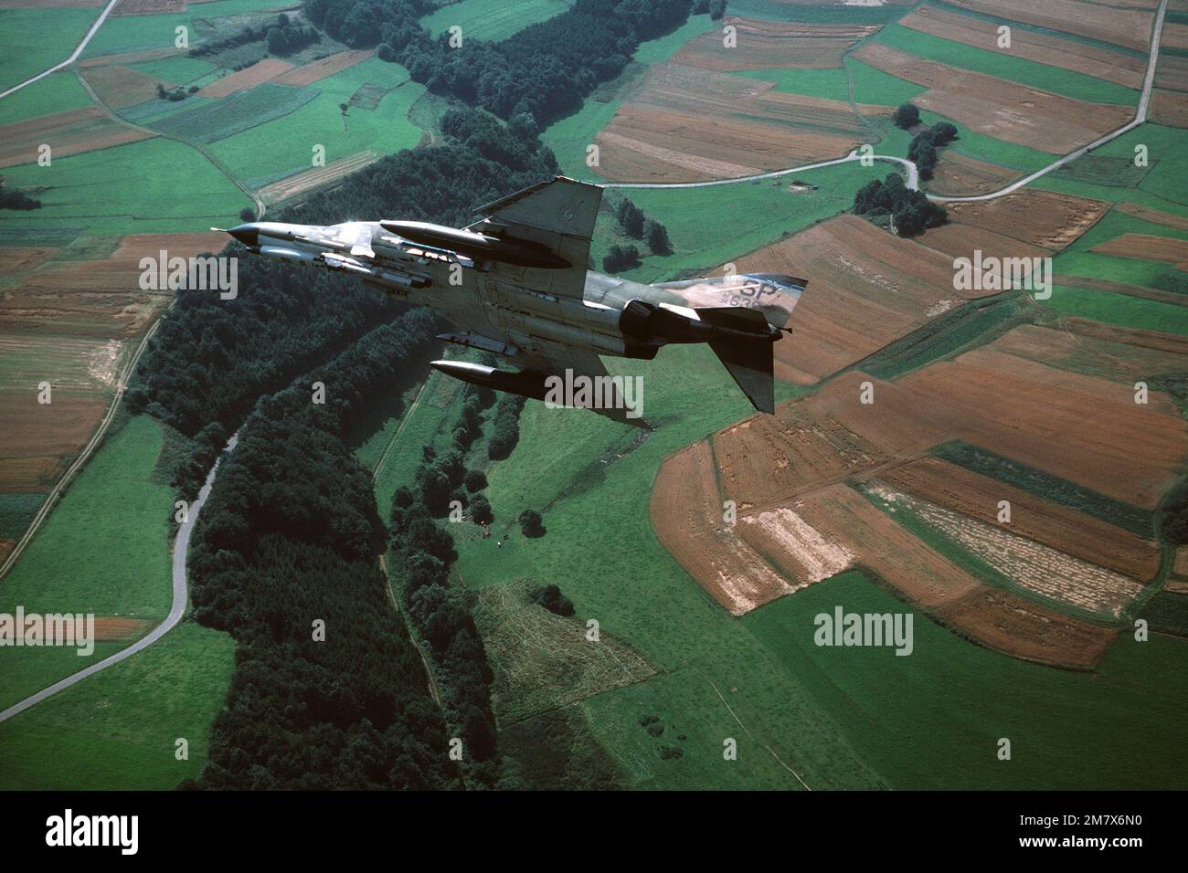 An air-to-air underside view of an F-4E Phantom II aircraft banking to ...
