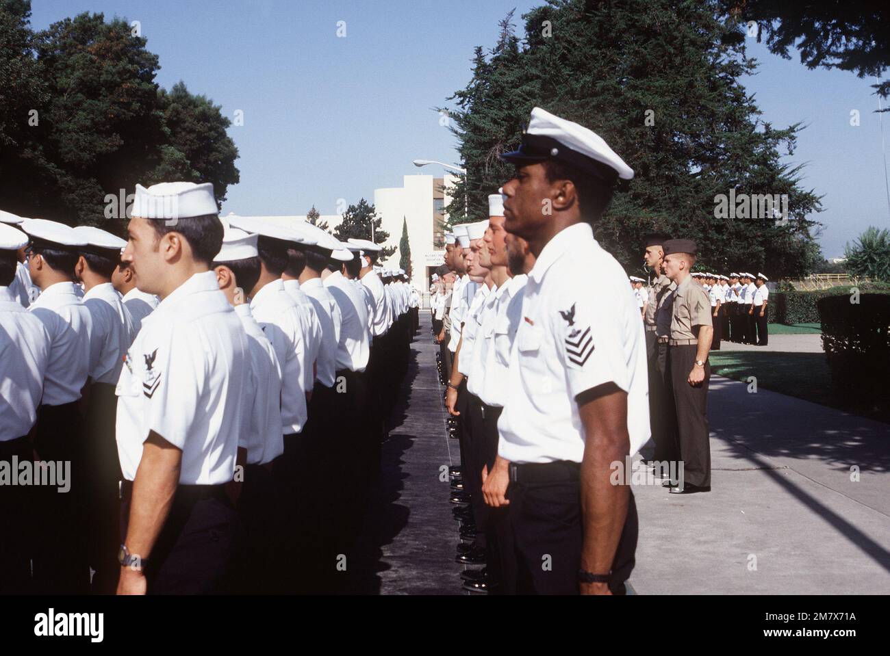 Navy and Marine personnel stand in ranks waiting for inspection. Base ...