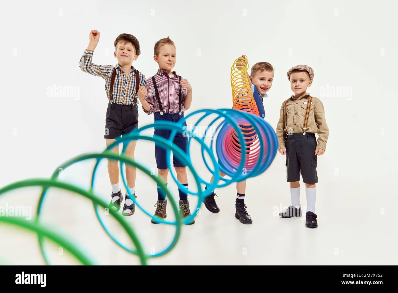 Group of childen, boys in classical retro clothes playing with slinky ...