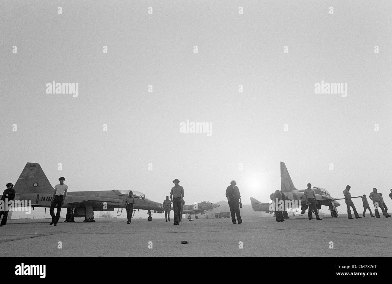 Maintenance crews walk onto a mist-covered flight line to prepare ...