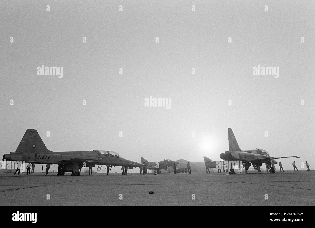 Maintenance crews walk onto a mist-covered flight line to prepare ...
