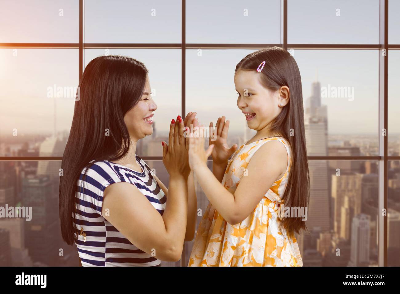 Side view of woman and her daughter are playing clapping game ...