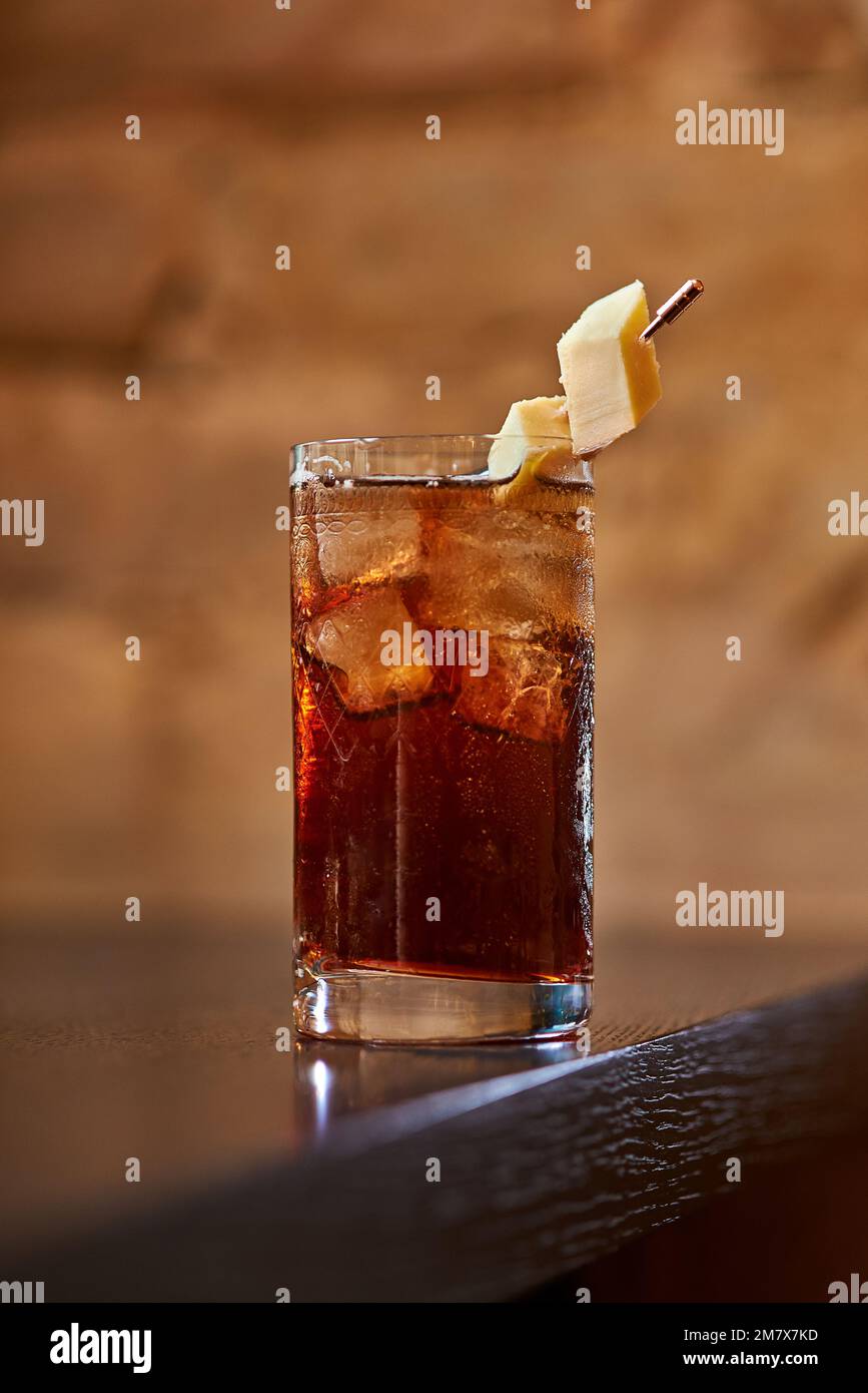 Brown Alcohol cocktail drink with ice cubes and cheese on background ...