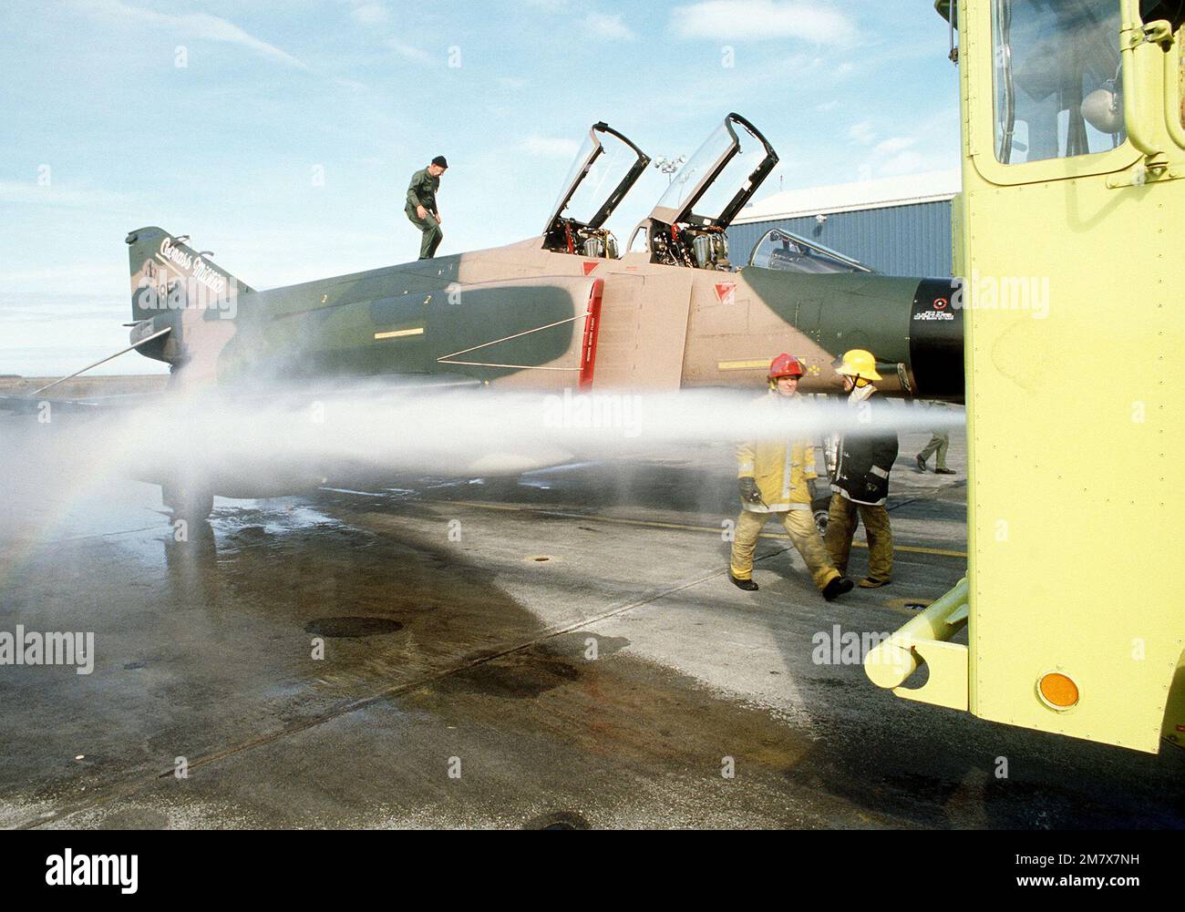 Fire fighters wash down a fuel spill from an F-4 Phantom II aircraft ...