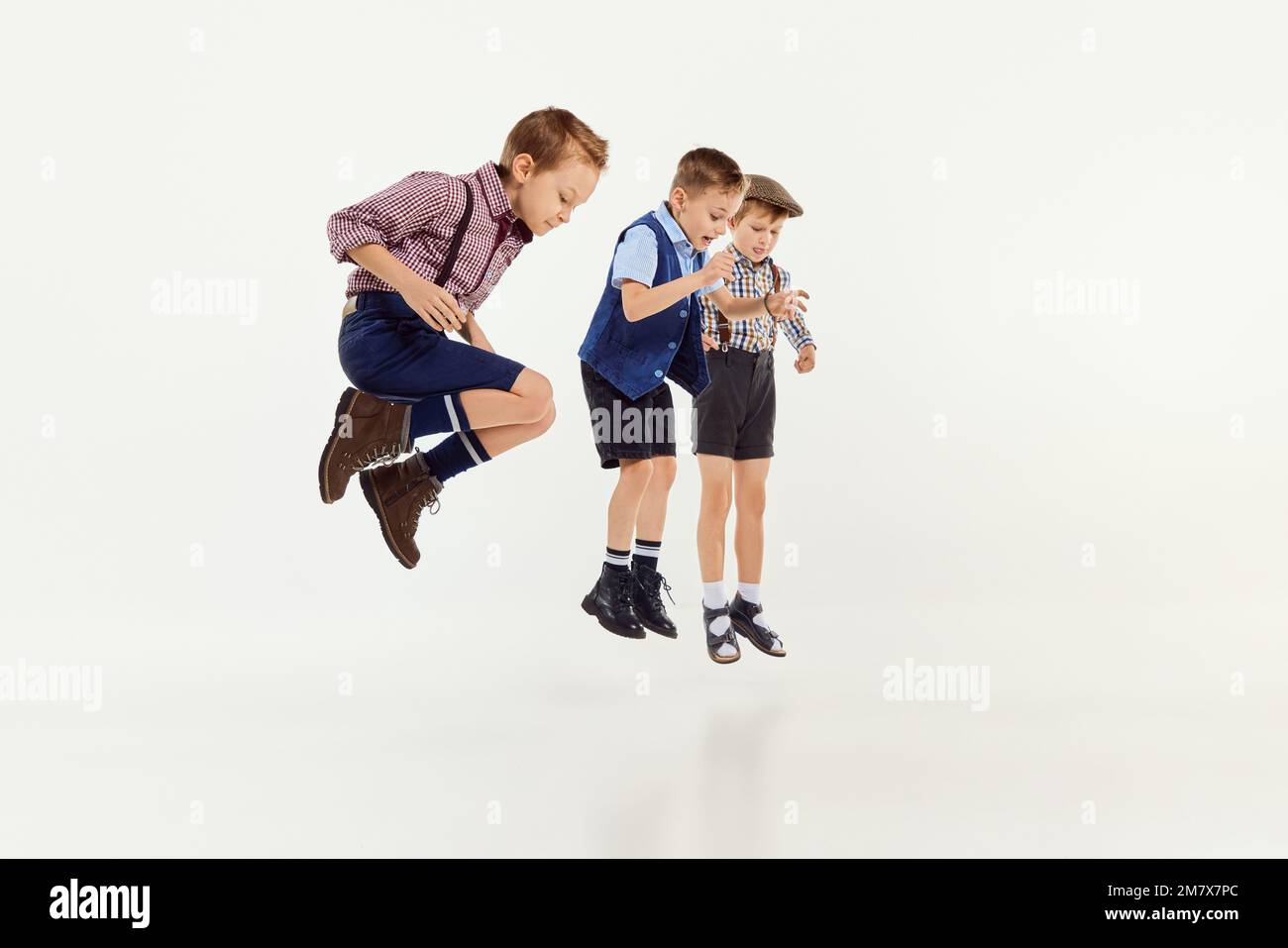 Three boys, children in classical retro clothes playing, jumping ...