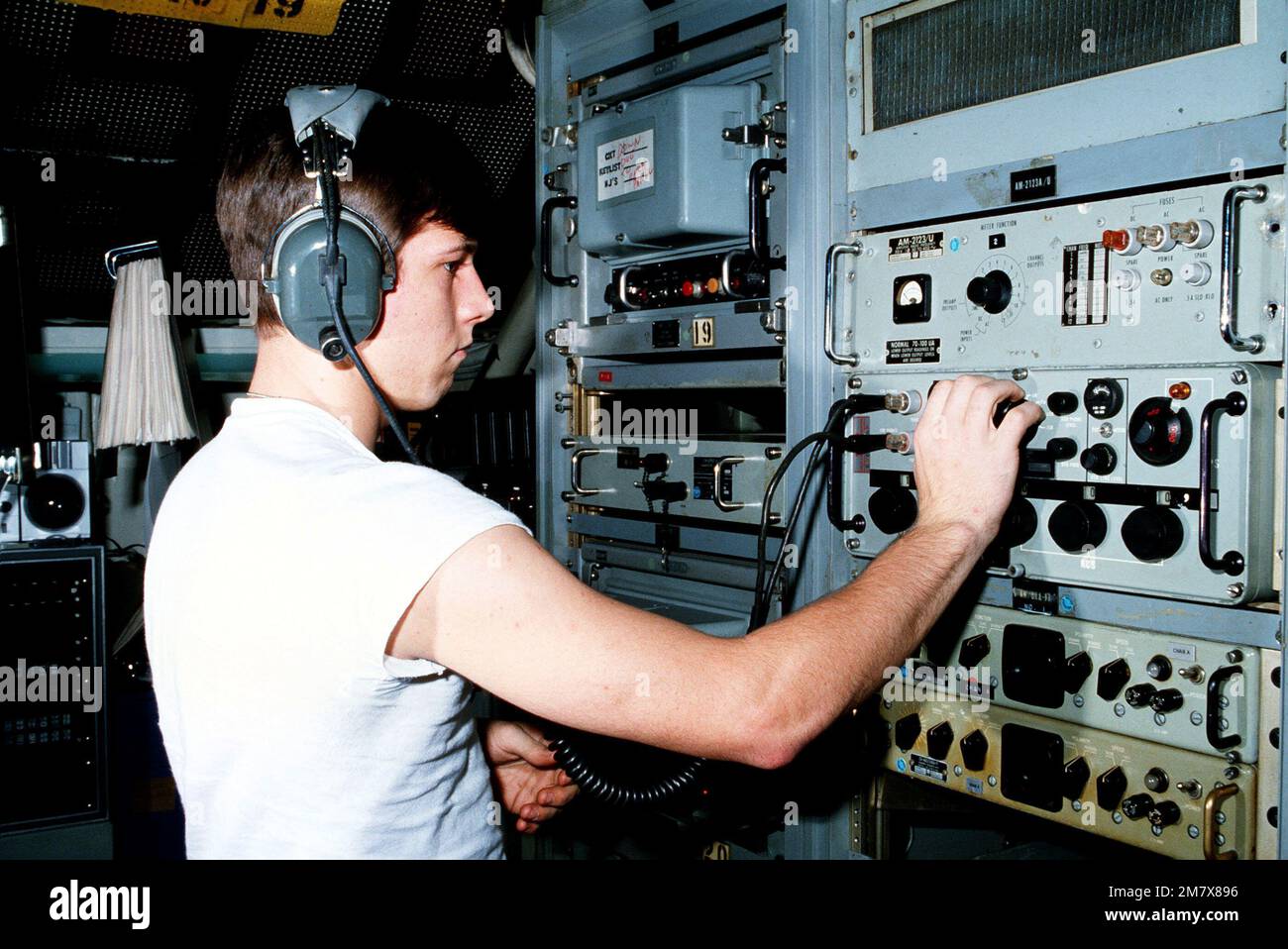 A radioman tunes a receiver in the radio shack on the aircraft carrier ...