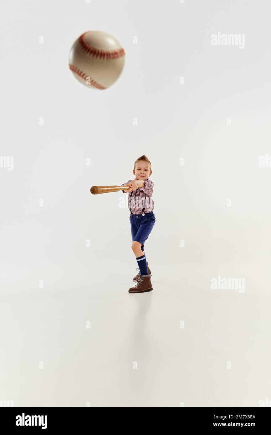 Hitting. Boy, child in classical retro clothes playing baseball over ...