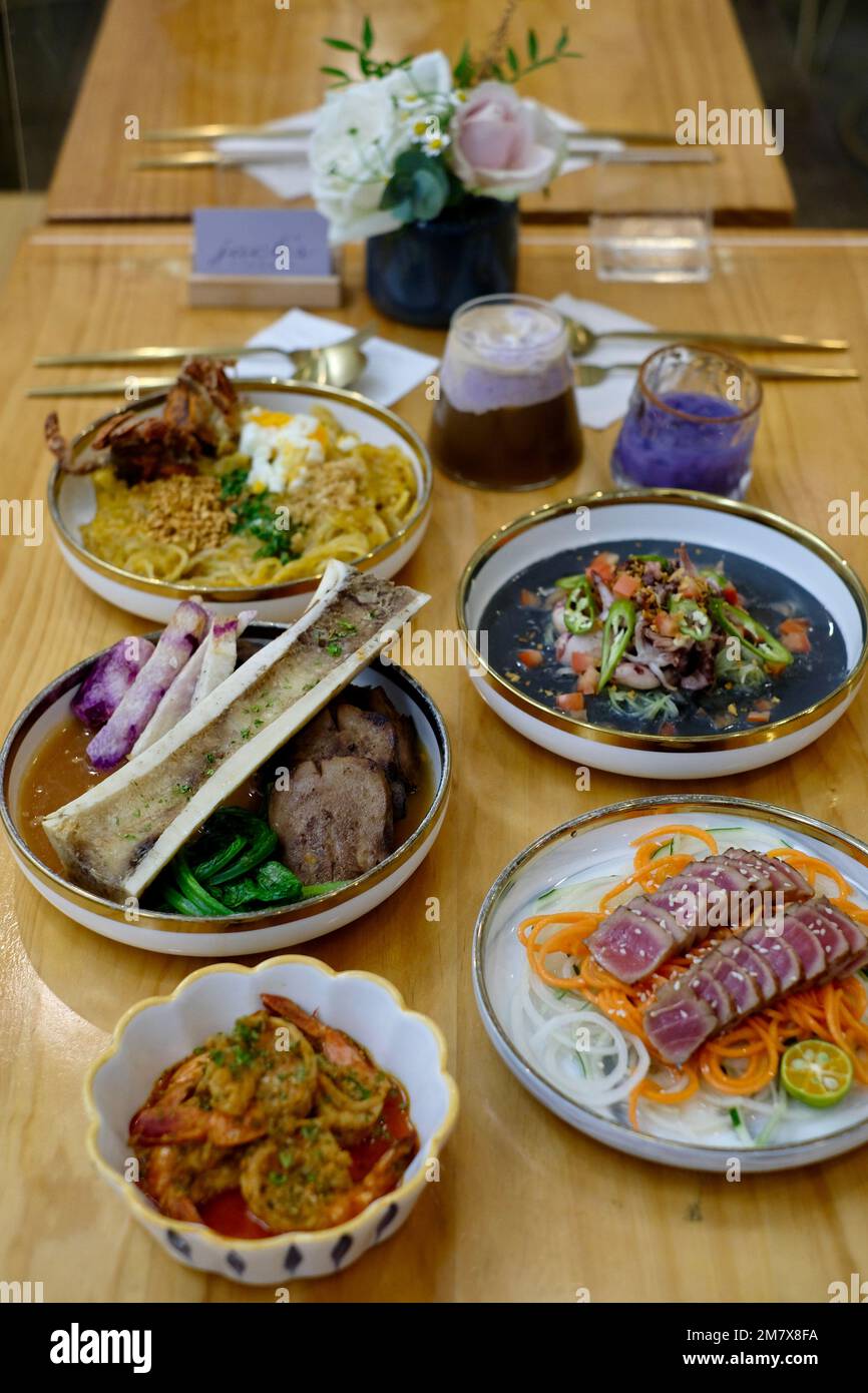 A closeup of a long wooden table with various delicious Filipino dishes ...