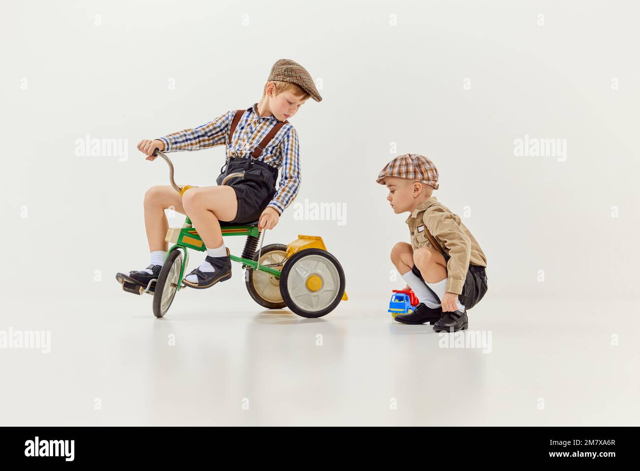 Friends playing. Boys, childred in retro clothes riding vintage bicycle ...