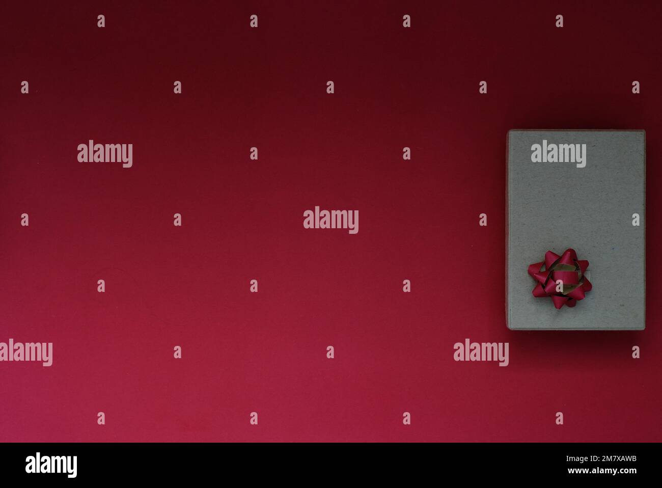 Brown gift box with a red ribbon on red background Stock Photo - Alamy