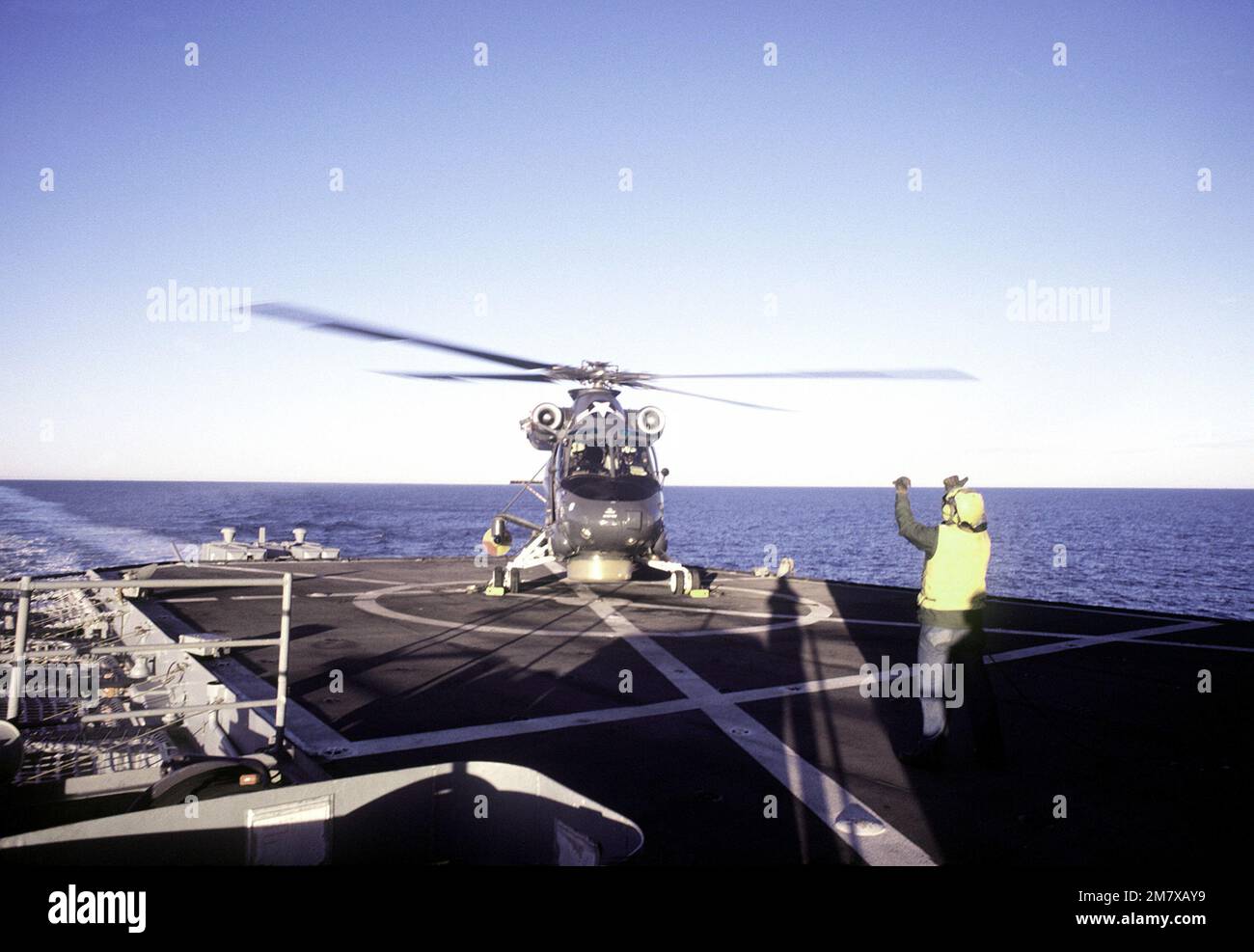 A flight deck crewman signals as SH-2F Seasprite light airborne multi ...