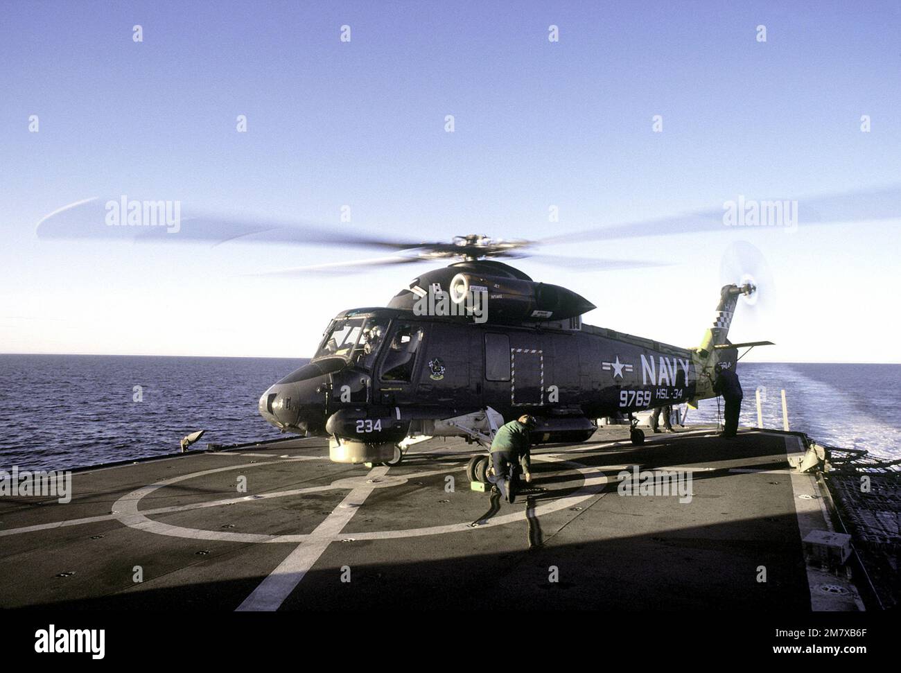 A flight deck crewman places chocks under the wheels of an SH-2F ...