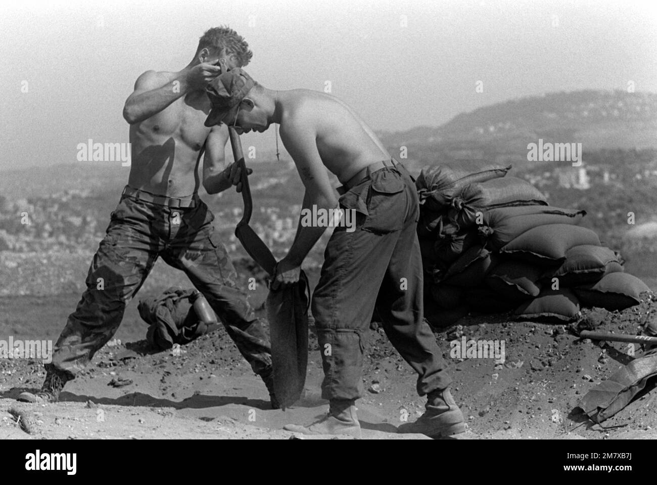 Two U.S. Marines fill sandbags that will be used around the perimeter ...