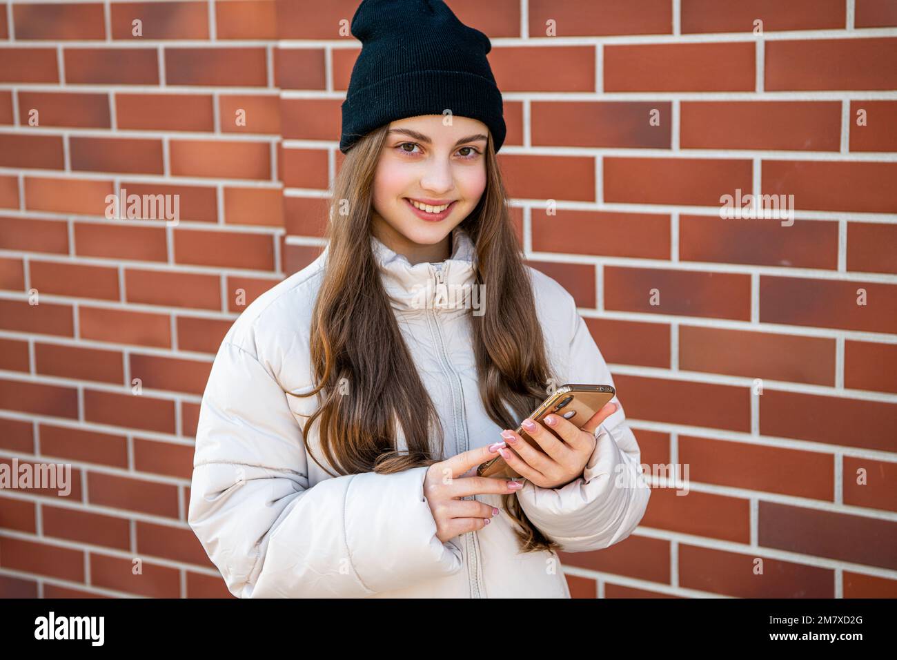 happy teen girl messaging on phone at brick background. teen girl ...