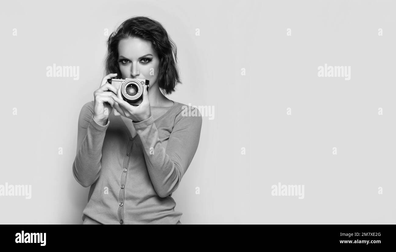 Serious girl photographing with photo camera beige background copy ...