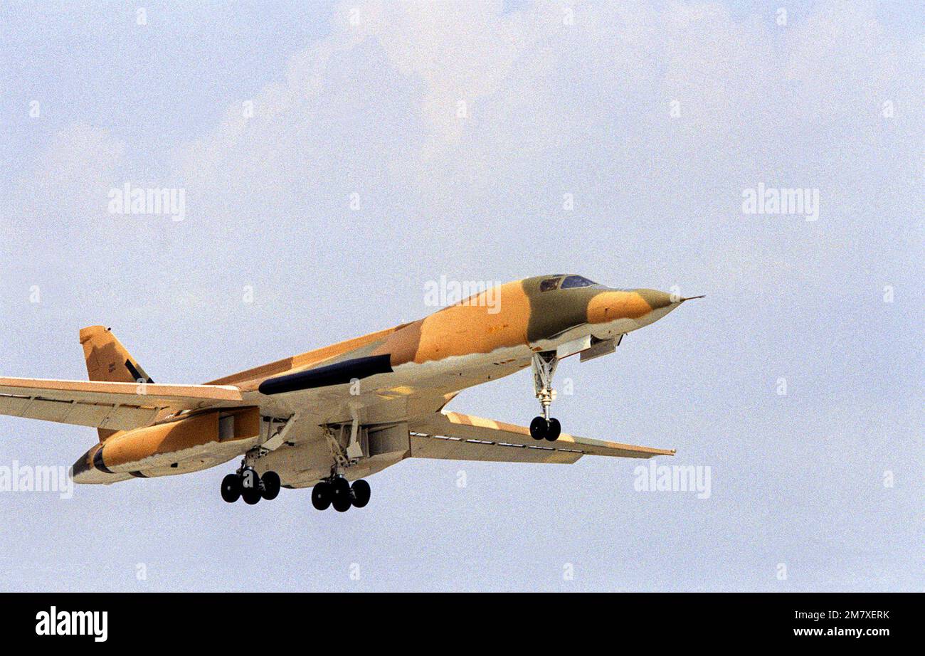 A ground-to-air right front view of a B-1 bomber flying over the runway ...