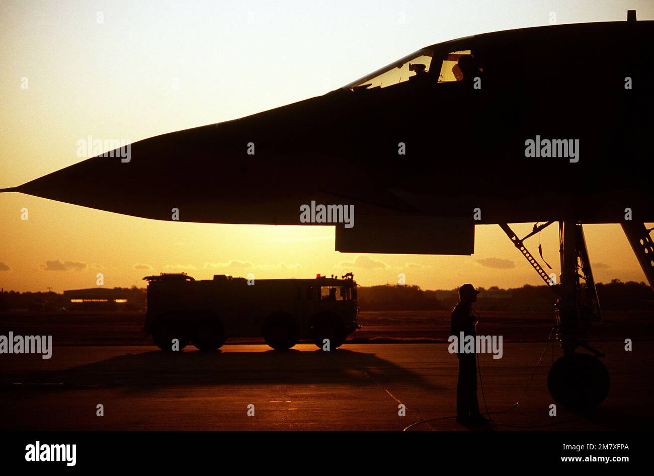 A silhouetted view of the front section of a B-1 bomber aircraft parked ...