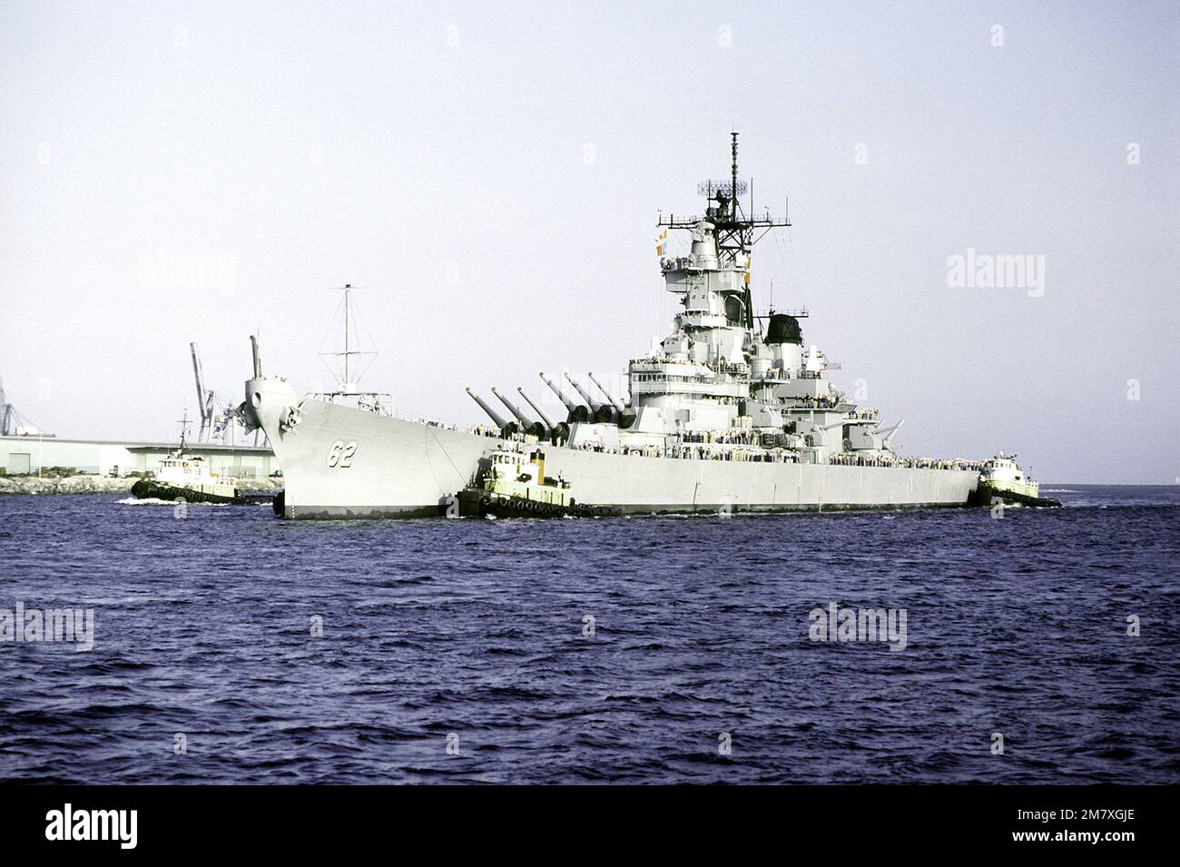 Port bow view of the battleship USS NEW JERSEY (BB-62) being towed from ...