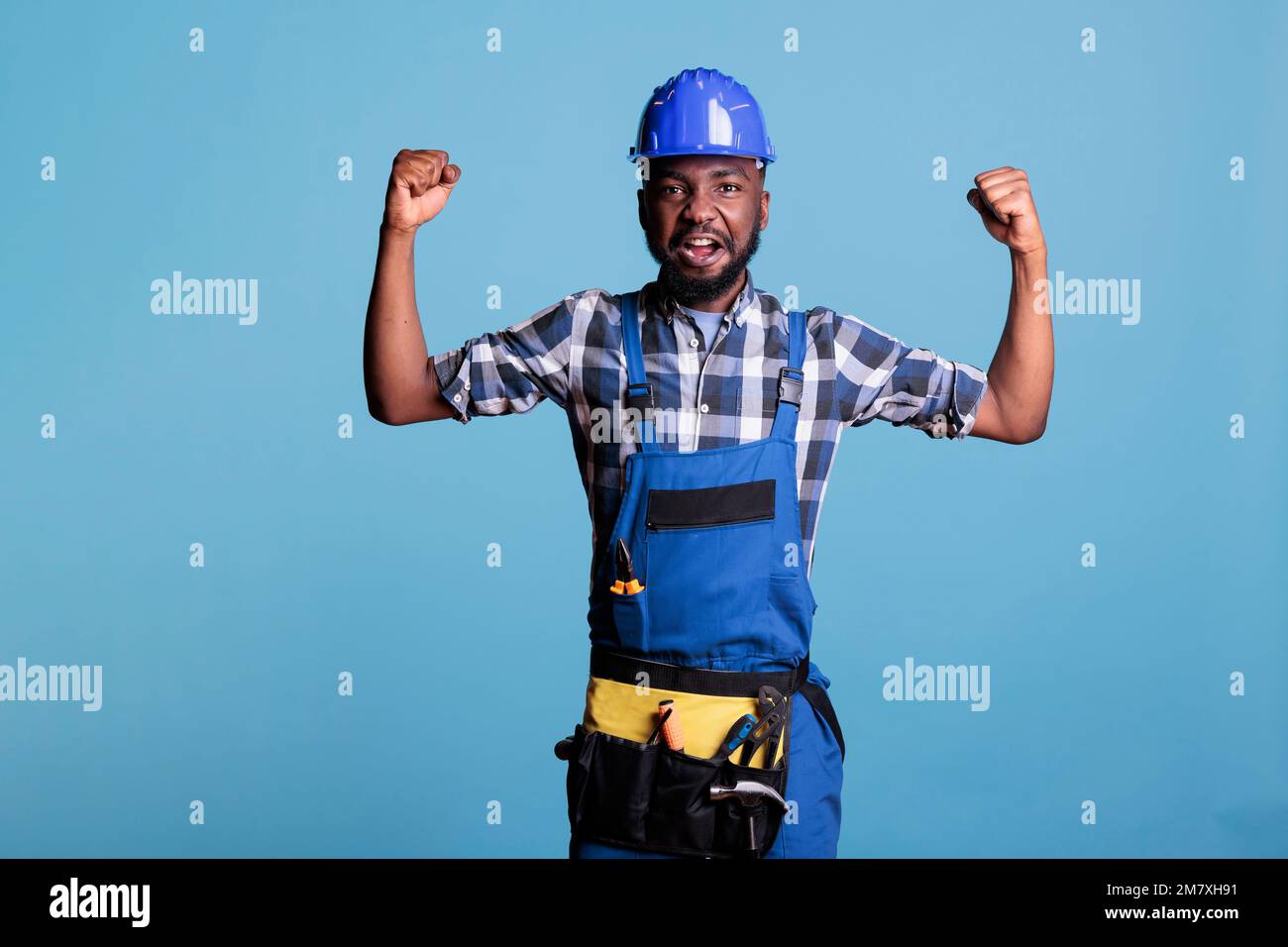 African american construction worker in coveralls showing his arm ...