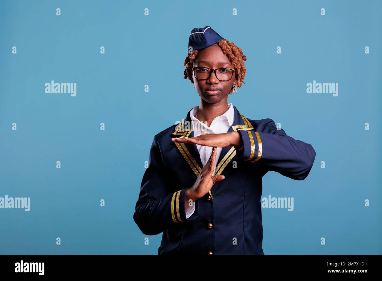 Tired female flight attendant gesturing time out and pause in studio ...