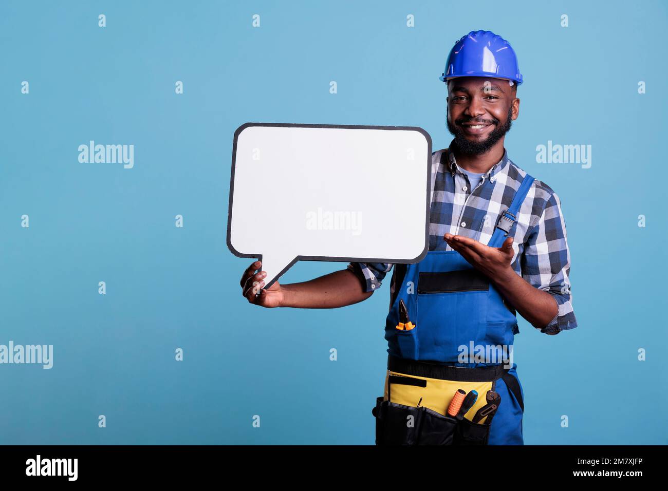 Smiling construction worker pointing to blank dialogue cloud with copy space, advertising mockup ...