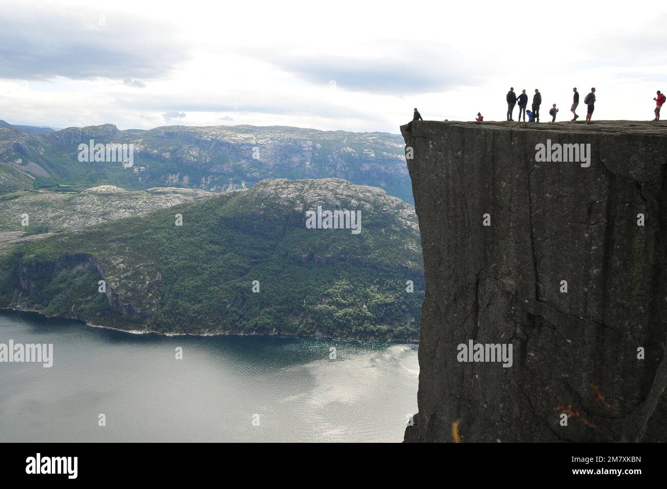 A group of people standing on the edge of a cliff in Preikestolen ...