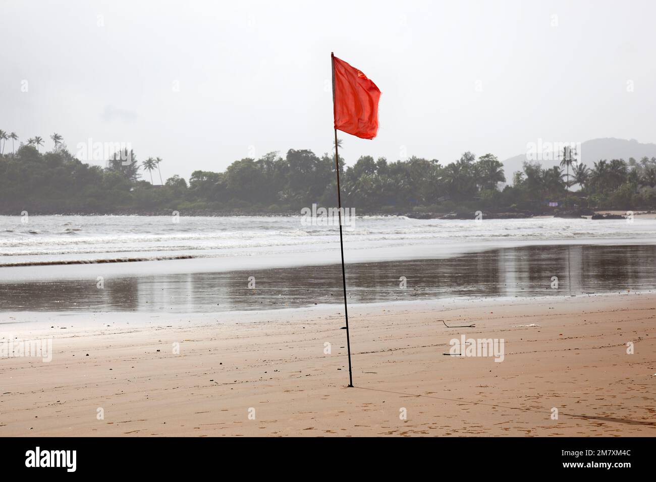 Patnem beach in Goa during the monsoon. The red flag warns of danger to ...