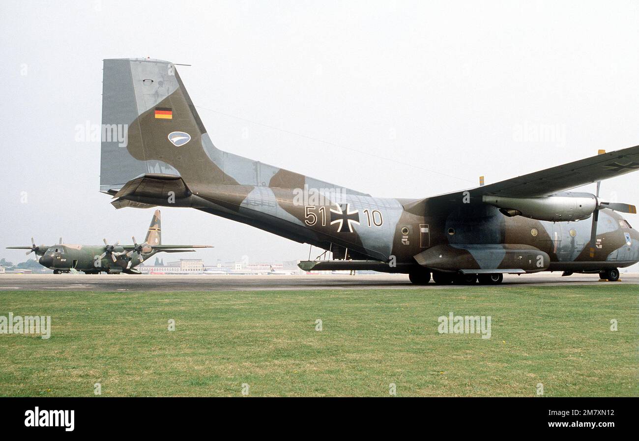 A C-130 Hercules aircraft, parked in the background, undergoes ...