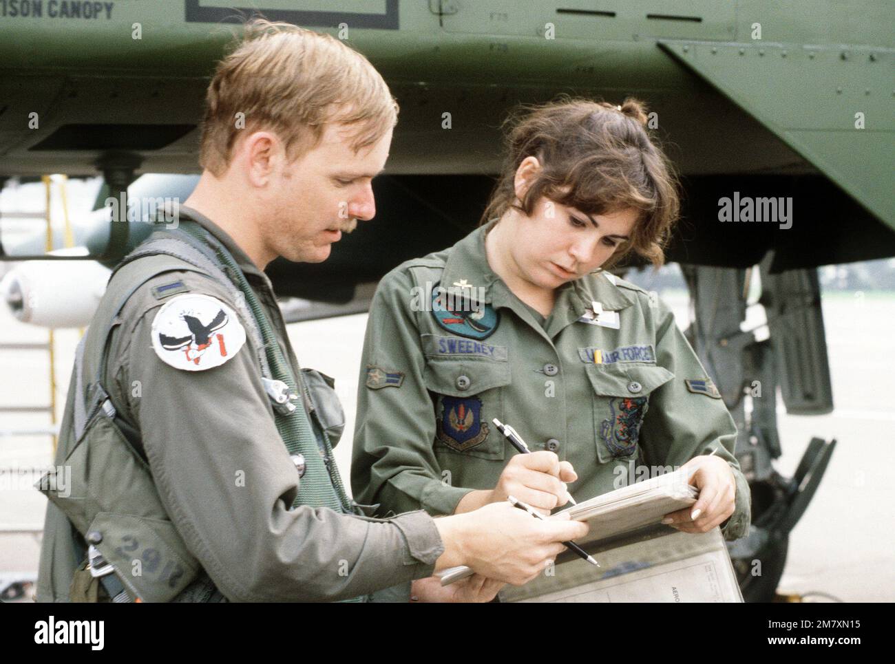 Flight personnel make entries in a log book while standing beside an A ...