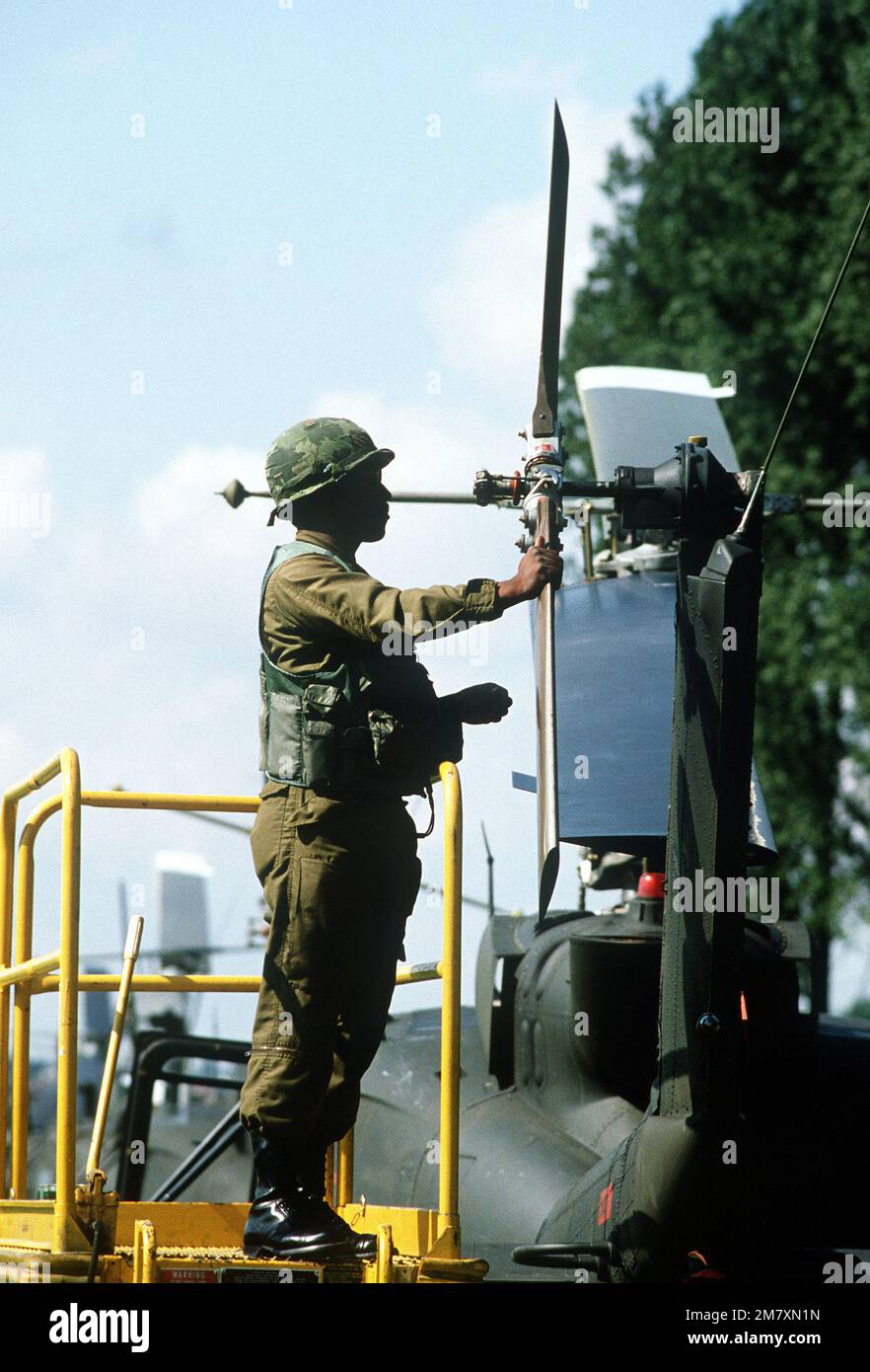 A ground crewman performs maintenance on a UH-IN Iroquois helicopter ...