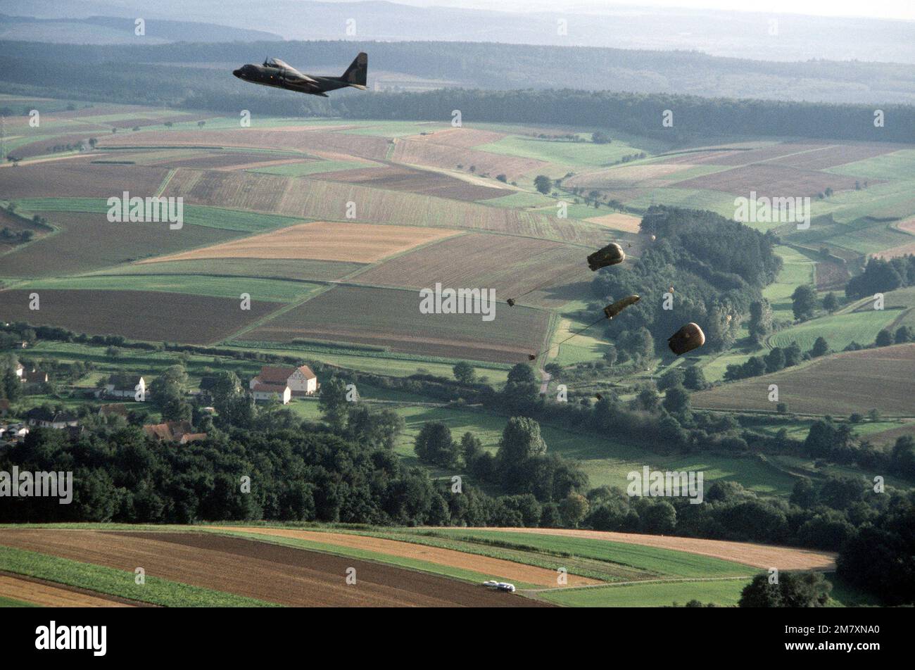 A C-130 Hercules aircraft releases three pallets containing c-rations ...