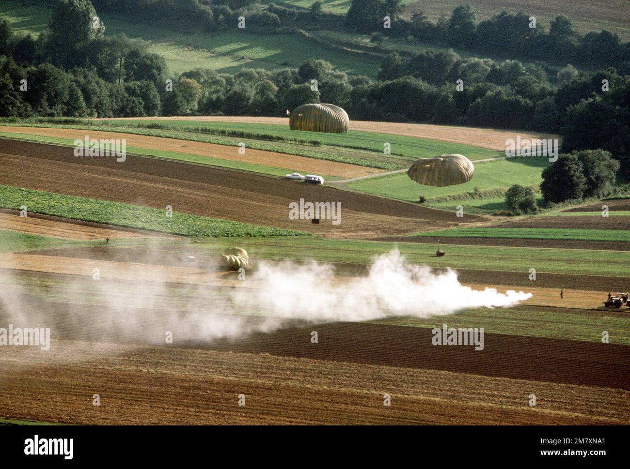 Three pallets dropped by parachute from a C-130 Hercules aircraft land ...